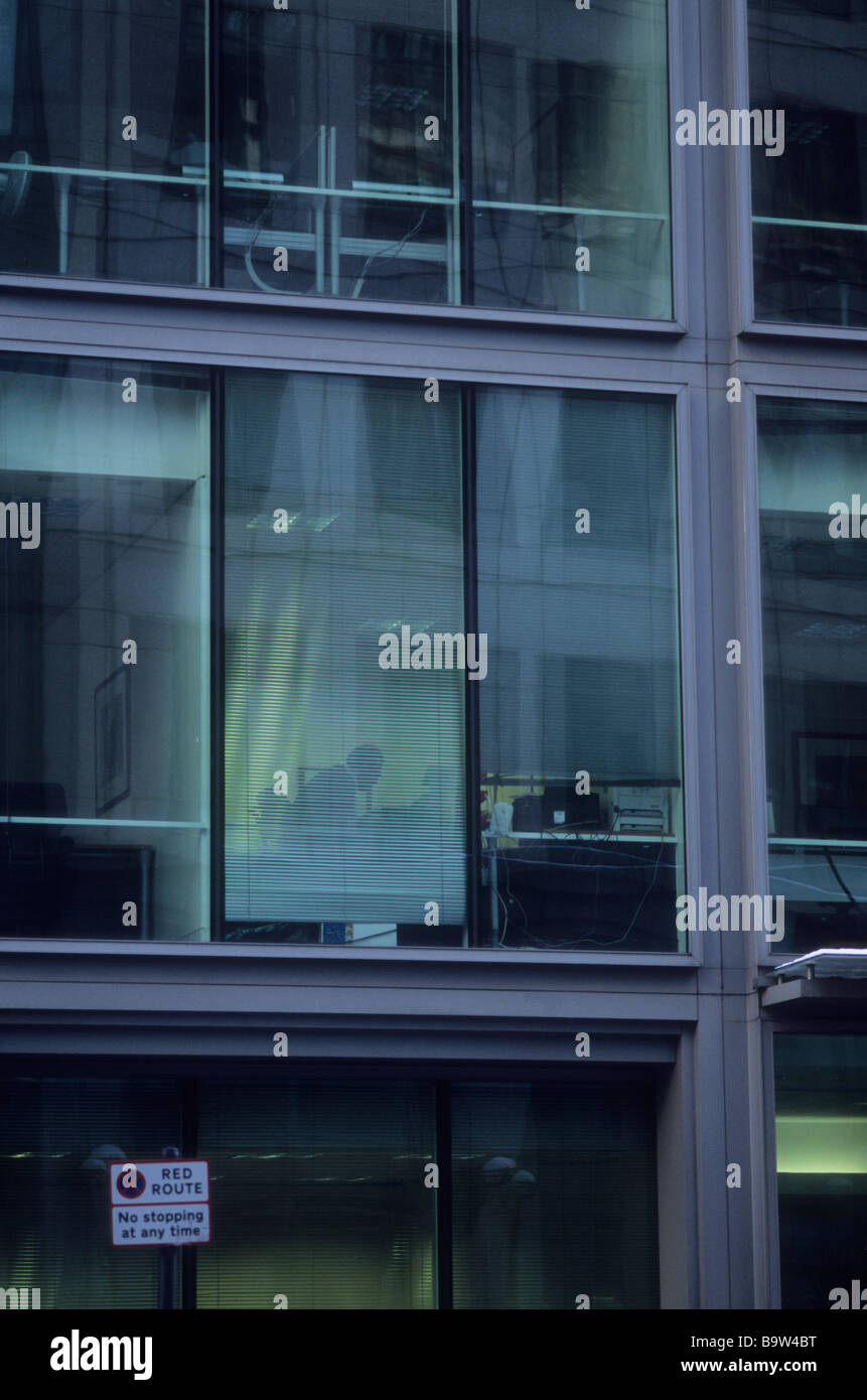 Man at desk just visible through blinded window Stock Photo - Alamy
