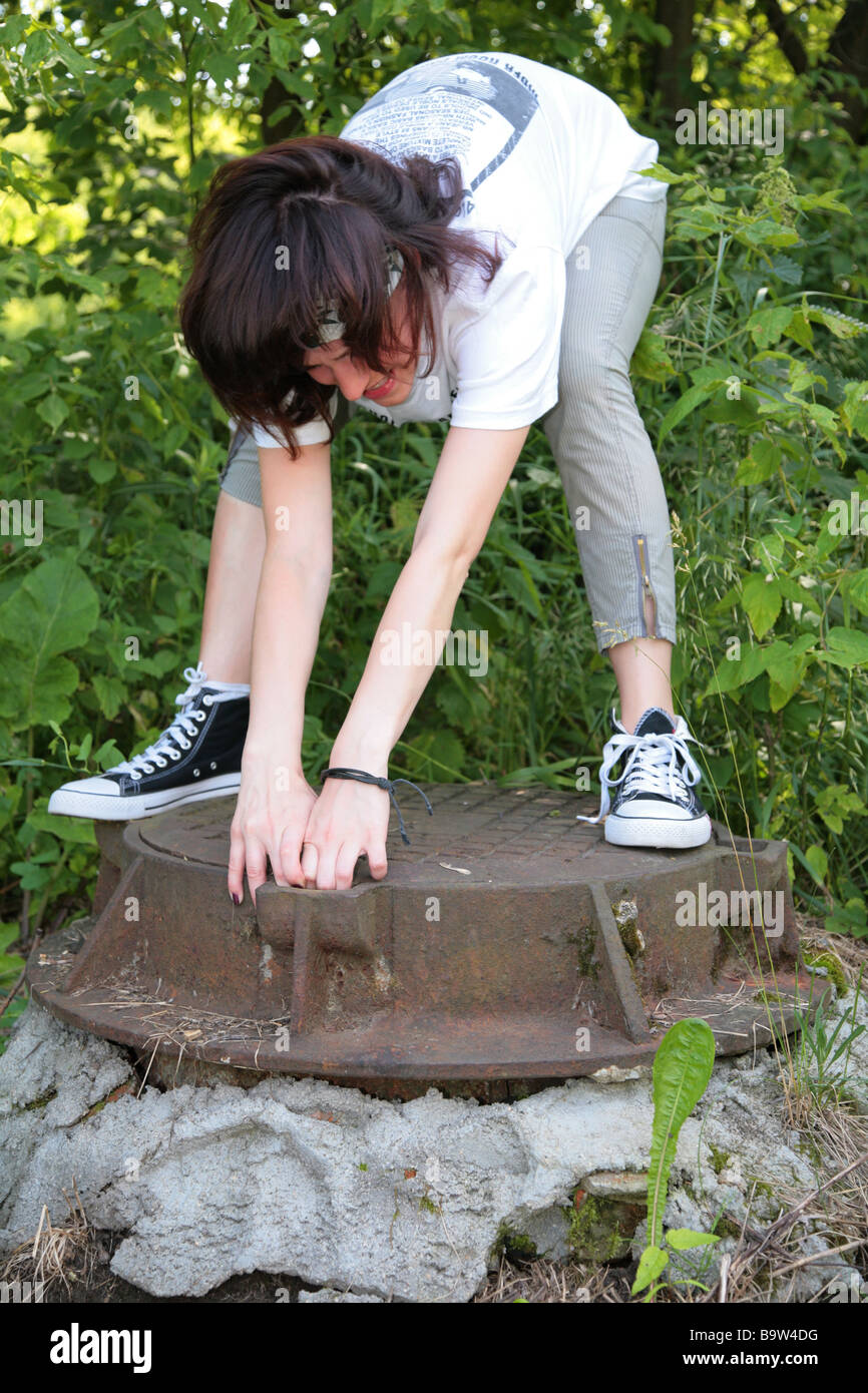 woman tries open iron hatch Stock Photo - Alamy