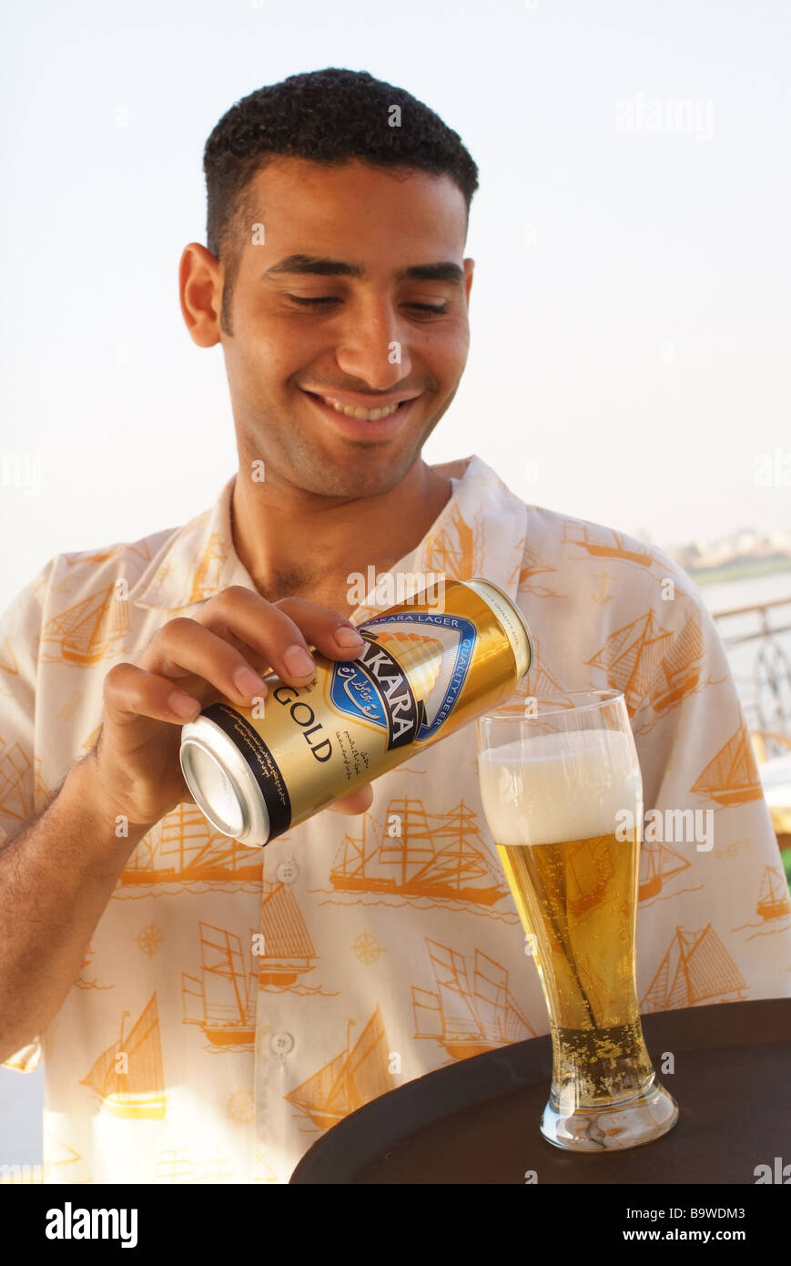 Egypt waiter pouring a Sakara beer for a passenger on a Nile River ...