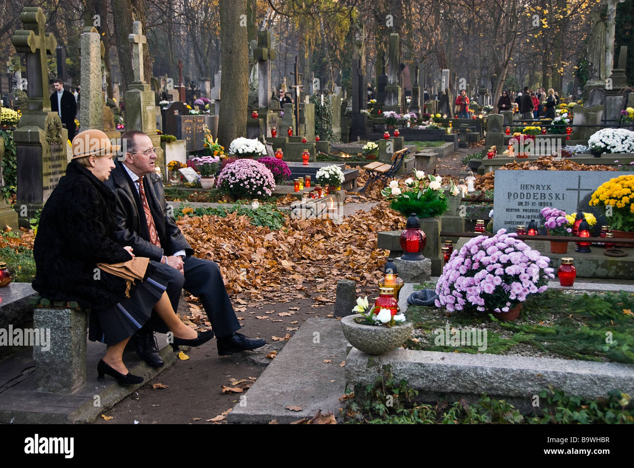 People sitting in front of a grave during the celebration of the All ...