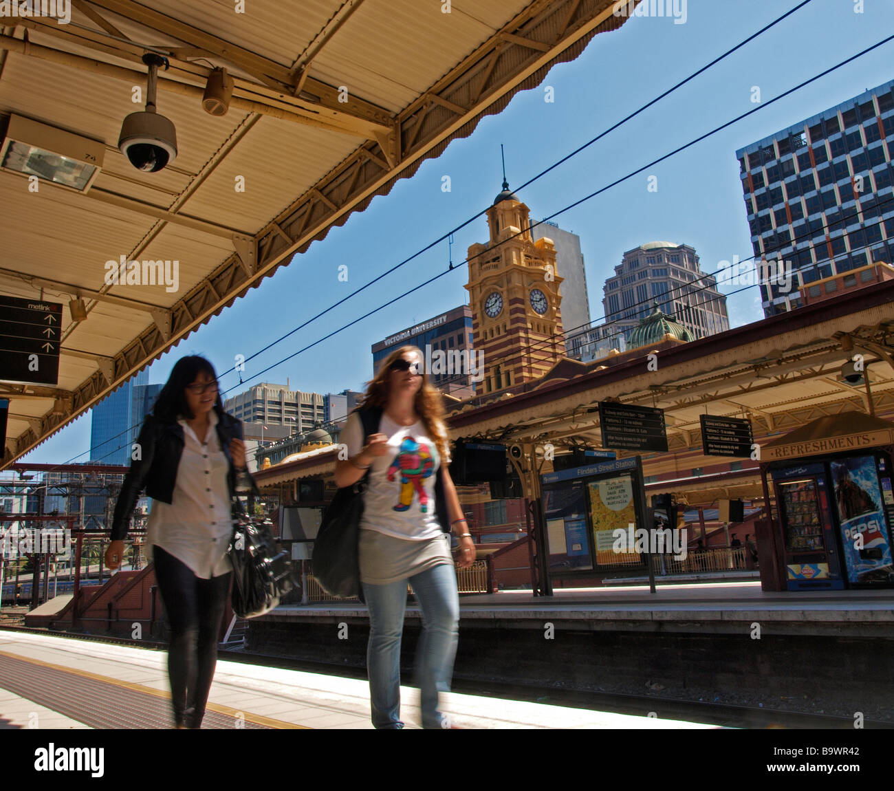 2 FEMALE PASSENGERS WALKING ALONG PLATFORM AT FLINDERS STREET RAILWAY ...