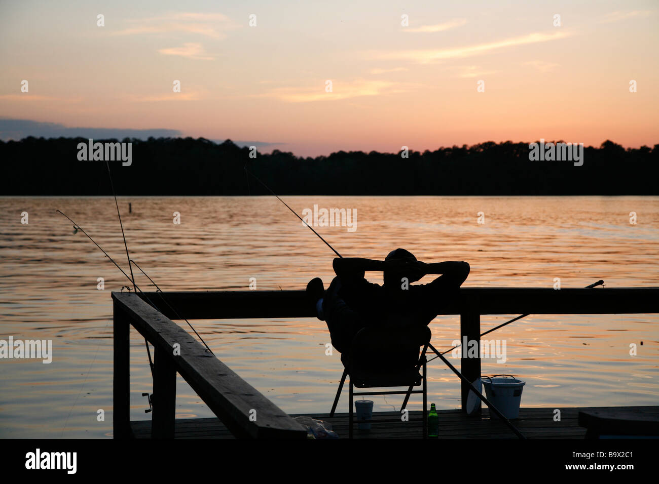 Man fishing from dock at sunset Stock Photo - Alamy