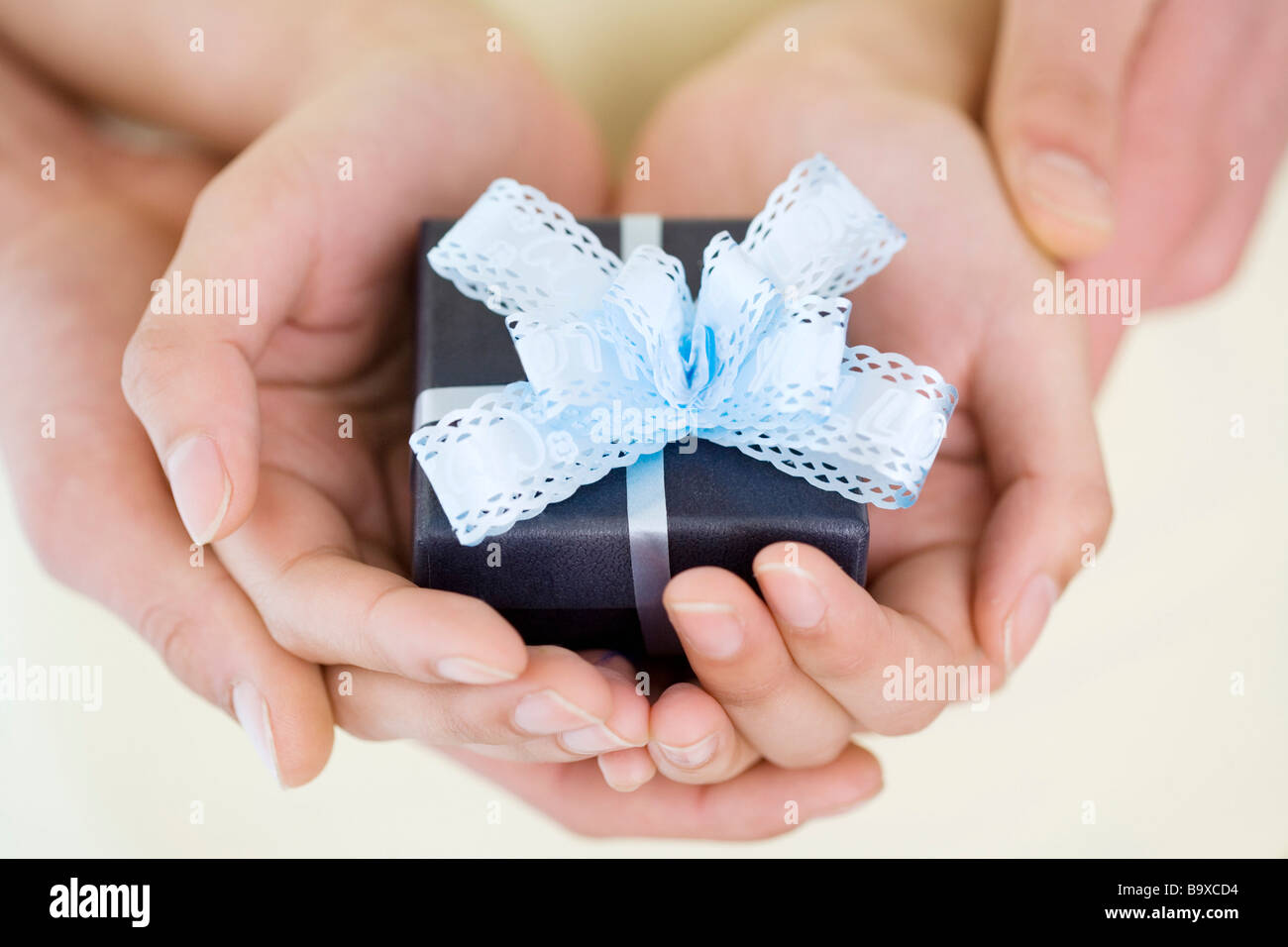 Young couple holding gift focus on hands Stock Photo - Alamy