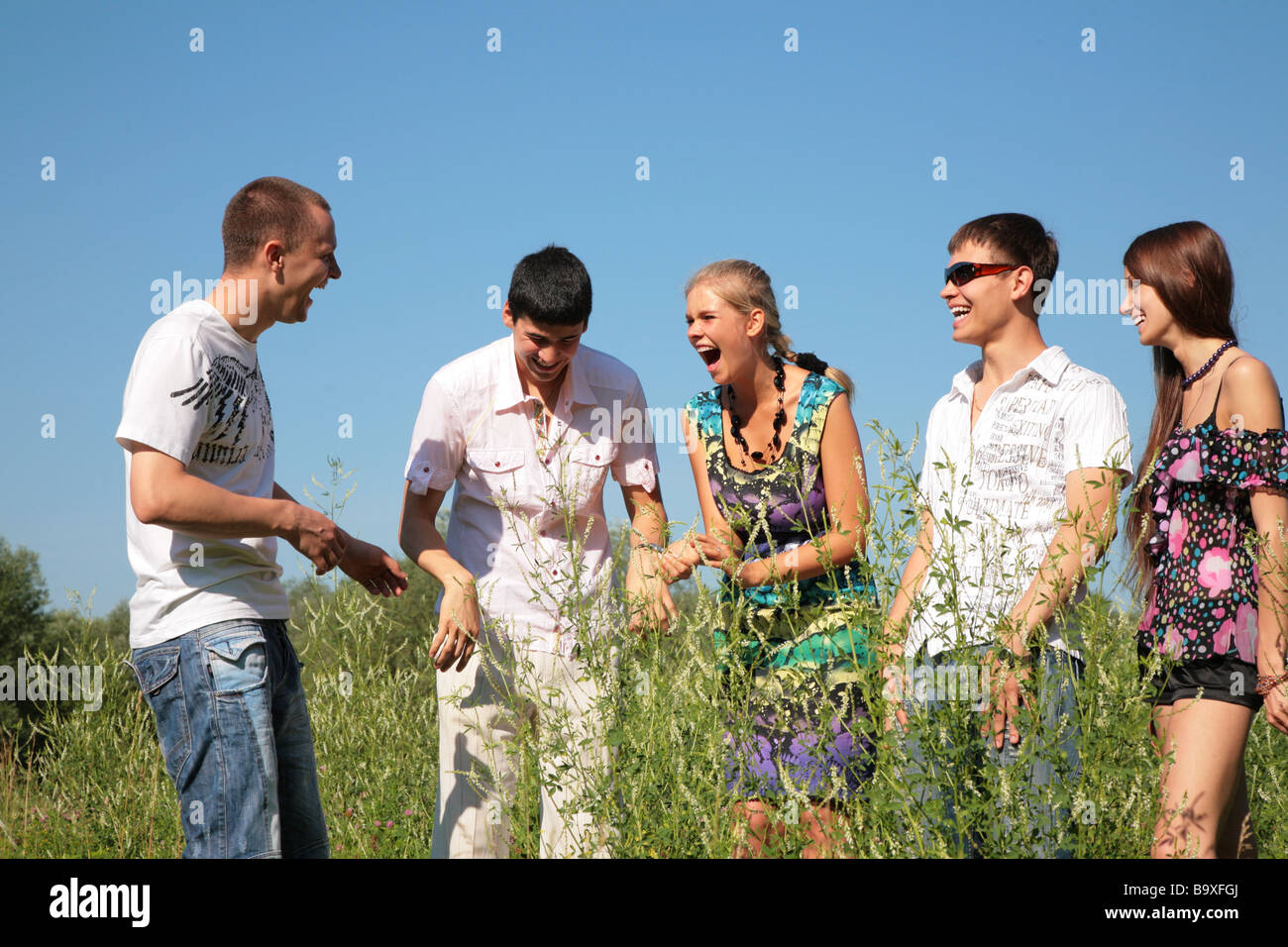 Group of five friends stands among grass Stock Photo - Alamy