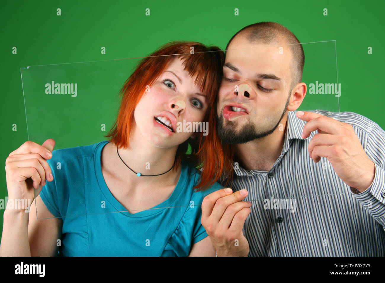 Close up girl with red hair and guy grimace behind glass Stock Photo ...