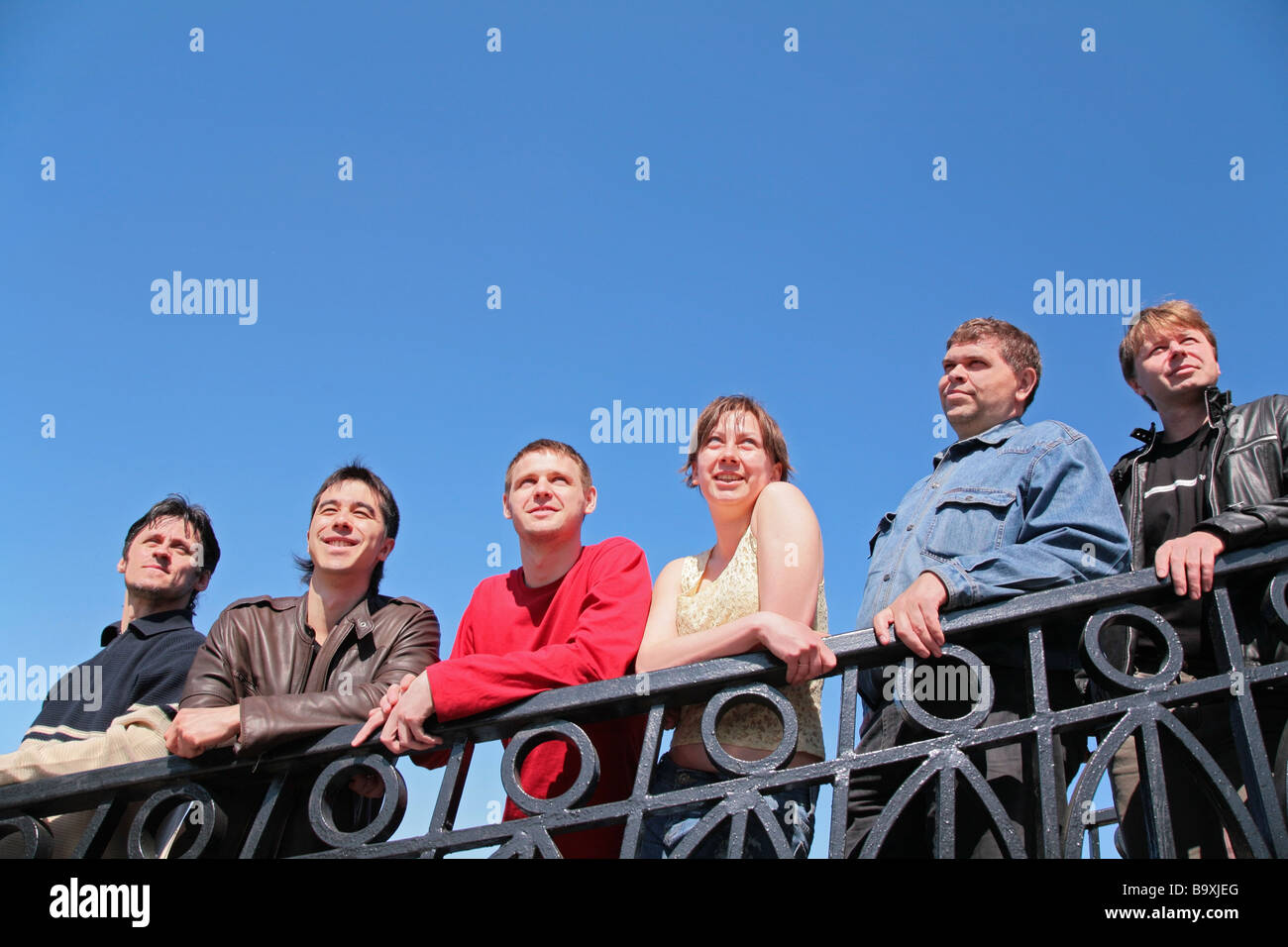 group of people stand leaning on handrail Stock Photo - Alamy