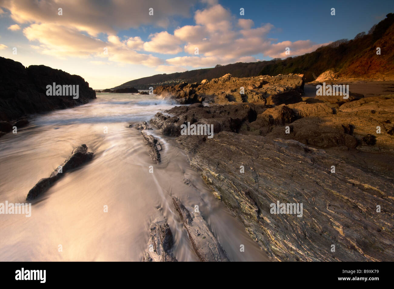 Waves rushing in around foreshore rocks on Stoke beach Devon UK Stock ...