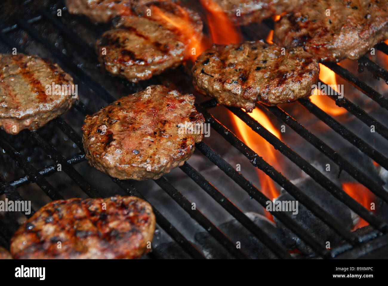 Hamburgers cooking on barbeque grill with flames Stock Photo - Alamy