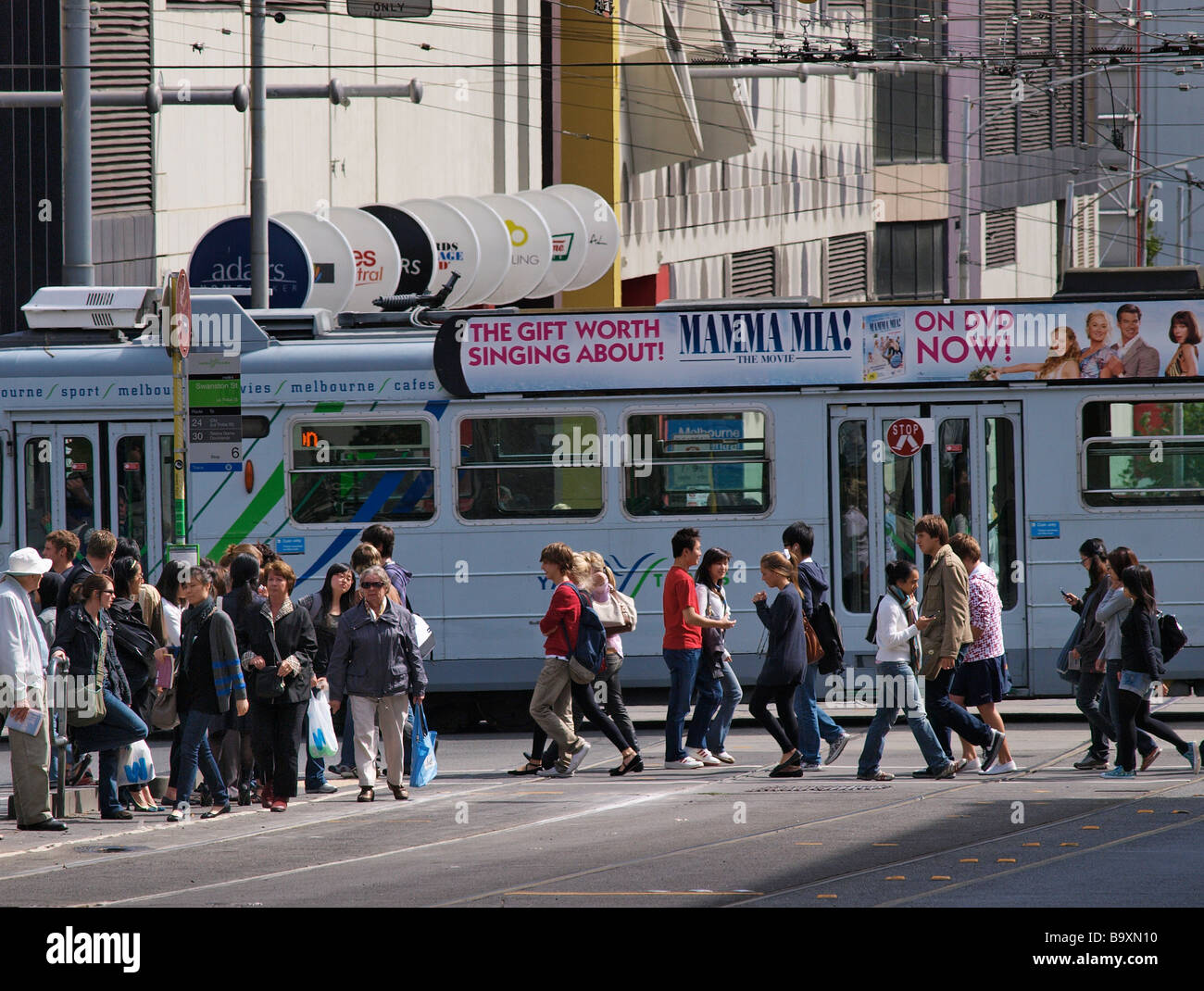 PEDESTRIANS CROSSING ROAD WITH TRAM IN BACKGROUND MELBOURNE VICTORIA ...