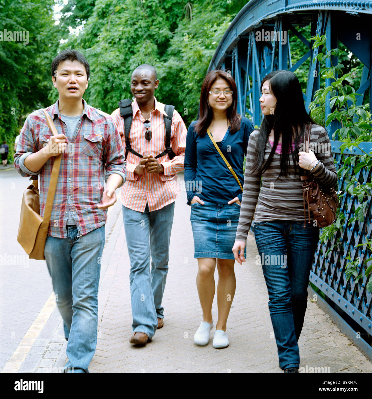 students, friends walking over a foot bridge in a city in England ...