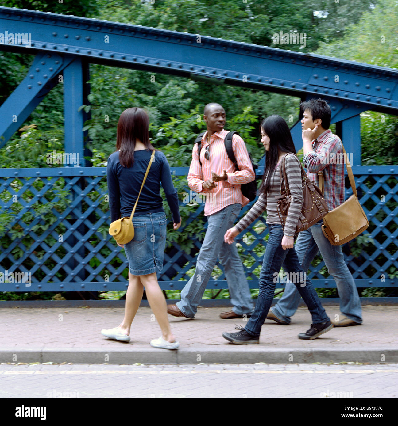 students, friends walking over a foot bridge in a city in England ...