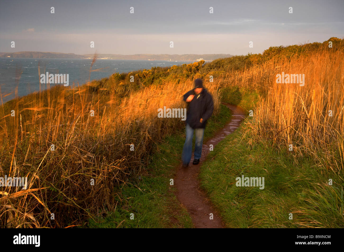 Man walking the coast path at Heybrook Bay on a dawn Winter morning ...
