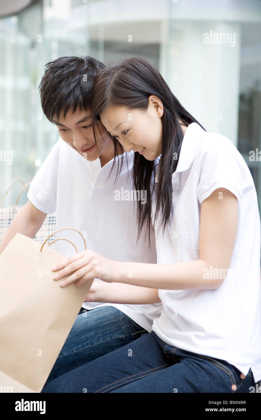Young couple looking things in shopping bag outdoors Stock Photo - Alamy