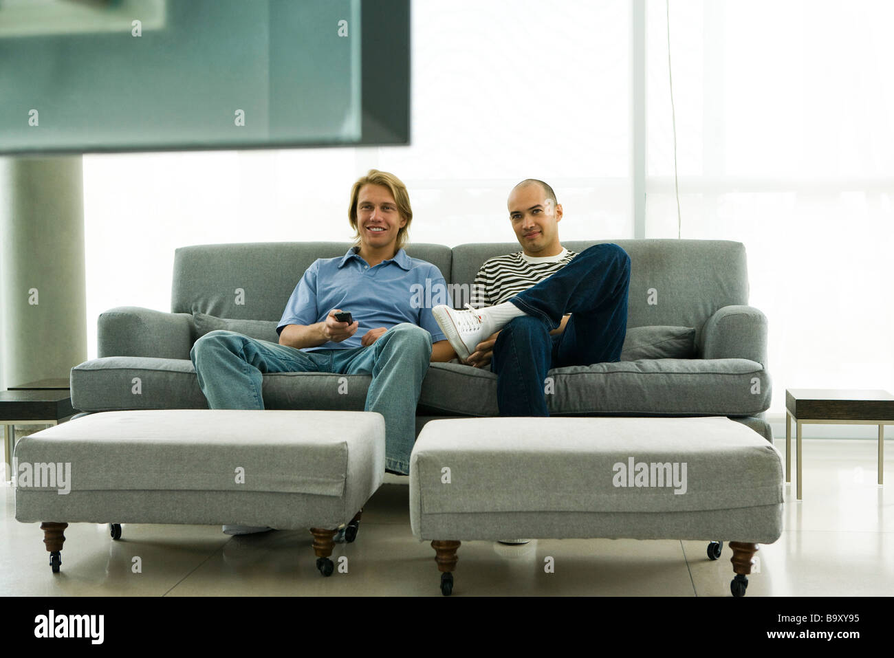 Two men sitting on sofa watching television Stock Photo - Alamy
