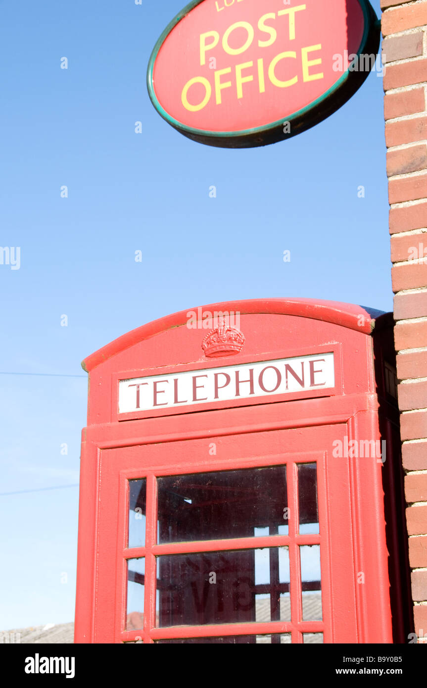 Red telephone box under Post office sign, blue sky Stock Photo - Alamy