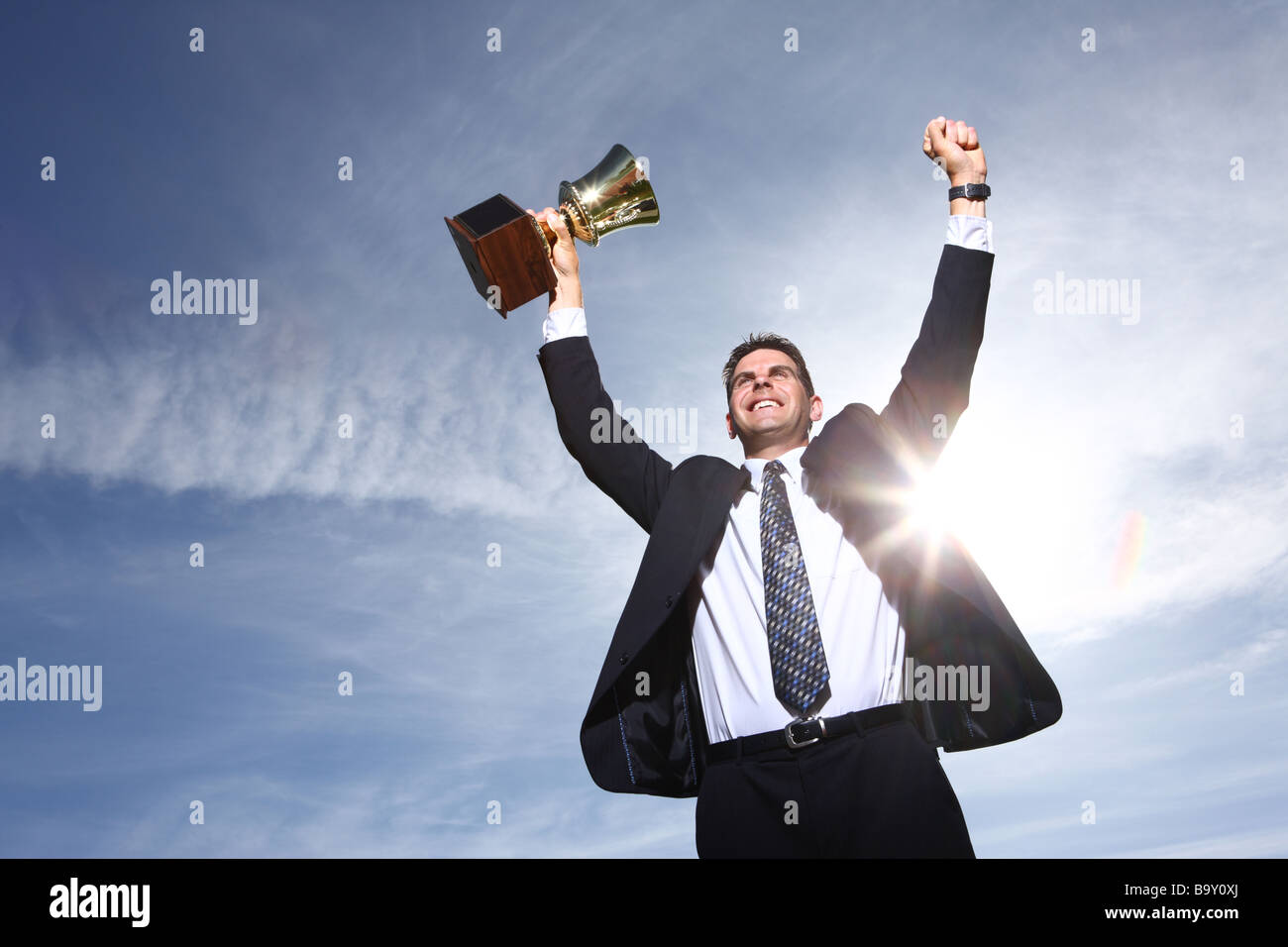 Businessman celebrating with trophy Stock Photo - Alamy