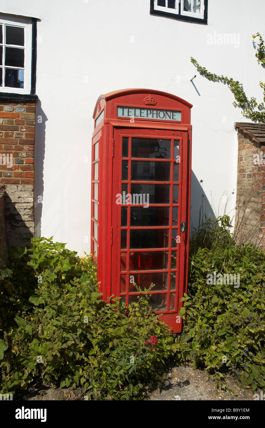 An old red telephone box by a white wall Stock Photo - Alamy