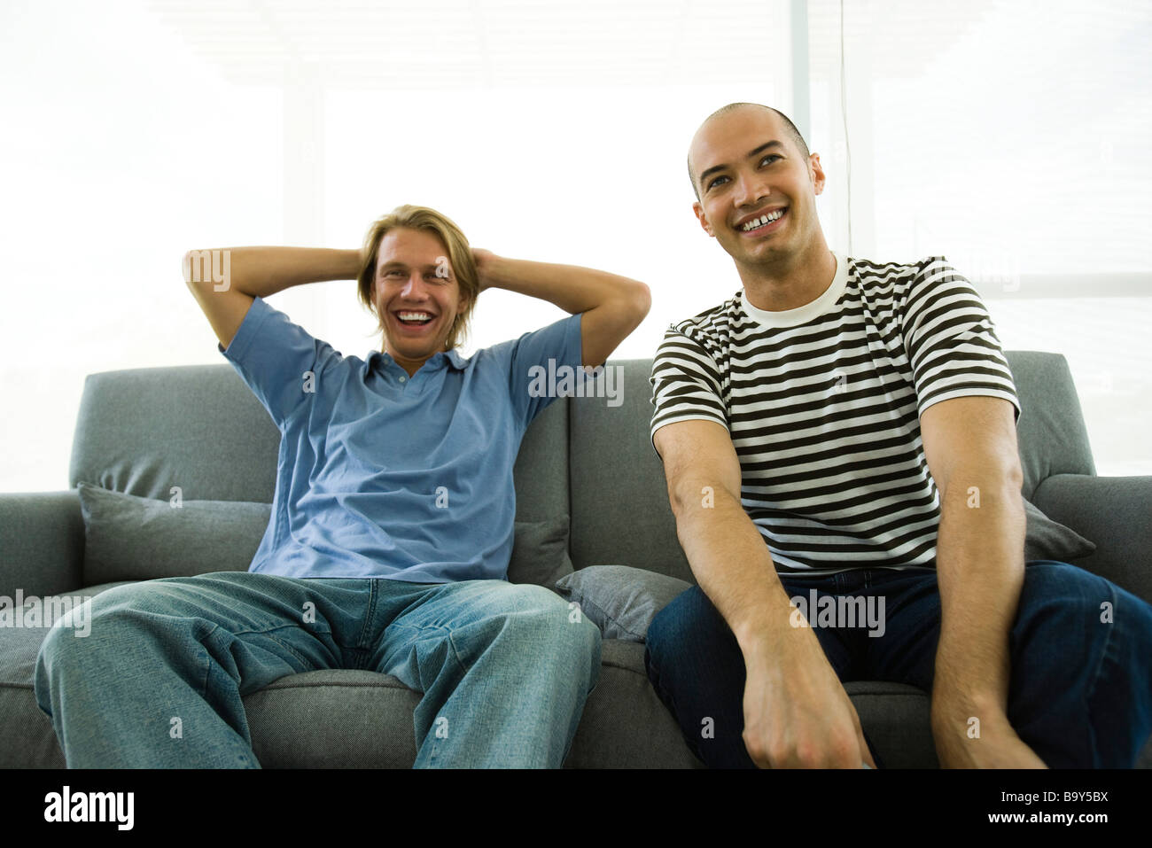 Two men sitting on sofa, laughing Stock Photo - Alamy