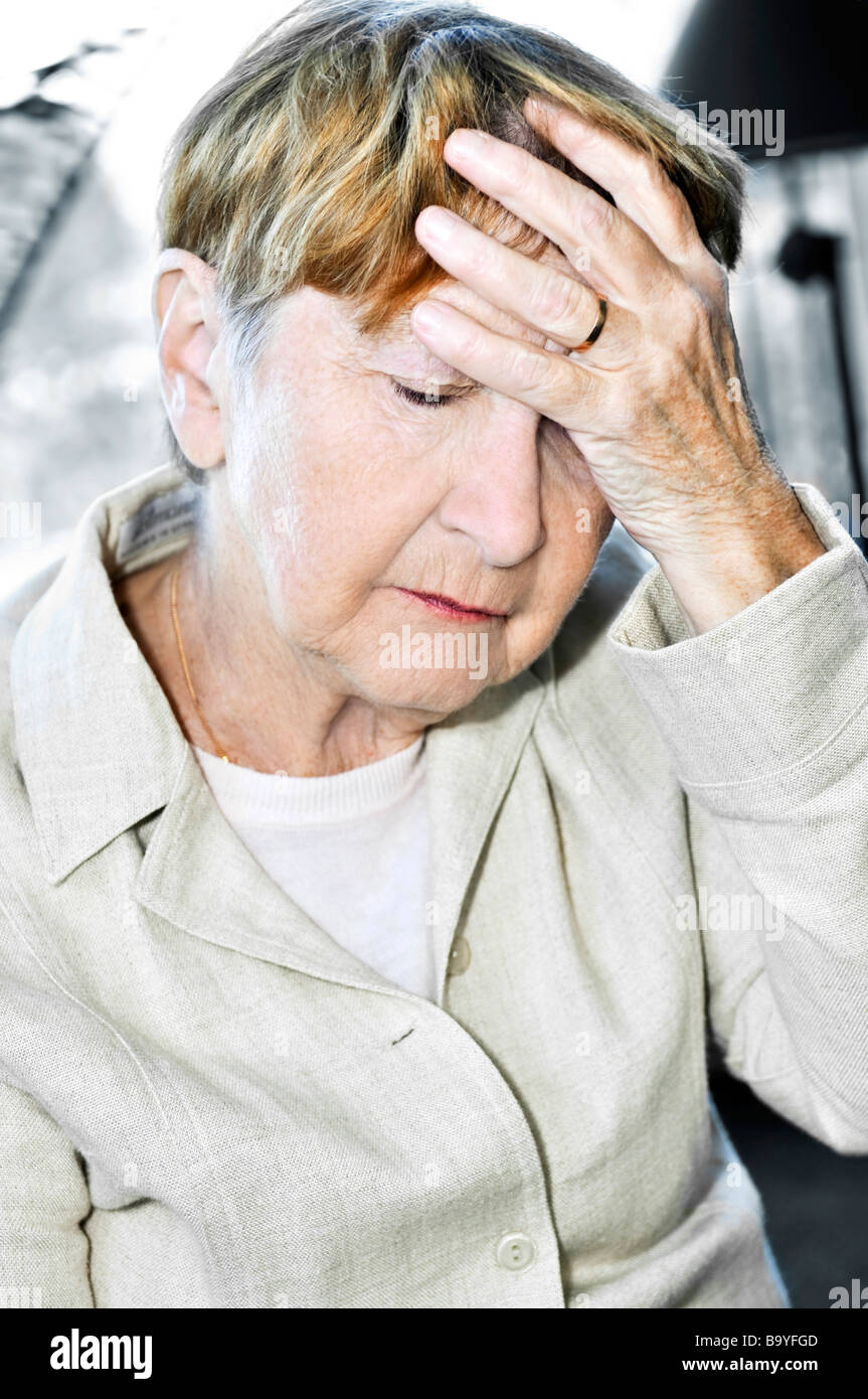 Sad senior woman holding her hand over forehead Stock Photo - Alamy