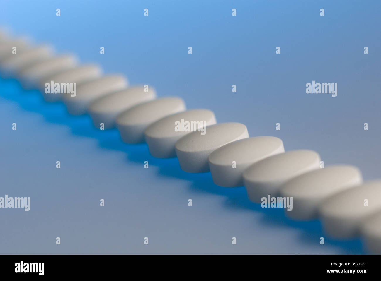 Single line of aspirin on a blue background Stock Photo - Alamy