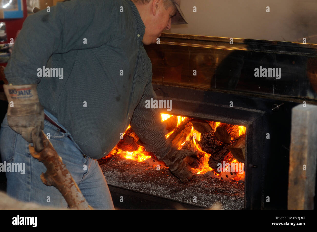 Man feeding fire of boiler making maple syrup Stock Photo - Alamy