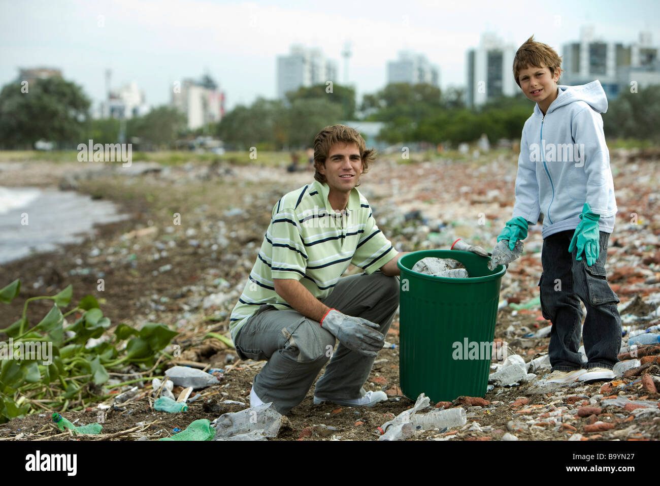 Young male and boy picking up trash on polluted shore Stock Photo - Alamy