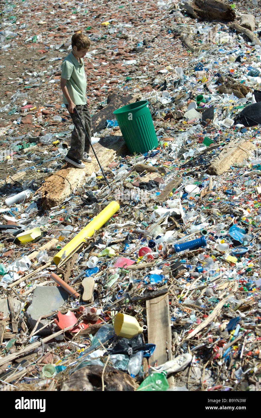 Boy standing in garbage dump, garbage can nearby, high angle view Stock ...