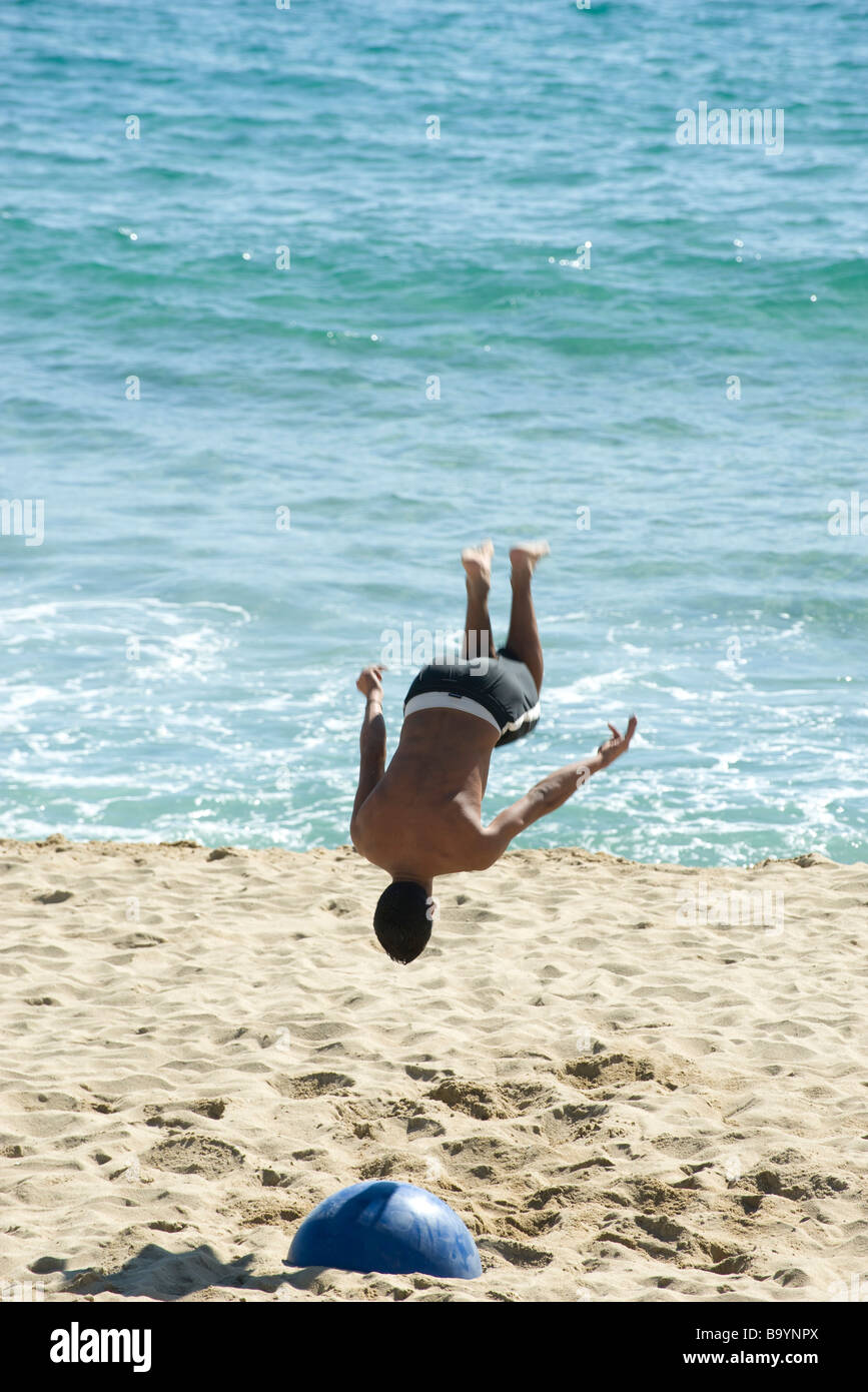 Teen boy doing back flip on beach Stock Photo - Alamy