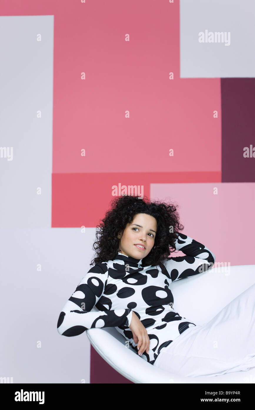 Young woman sitting in arm chair, thinking Stock Photo - Alamy