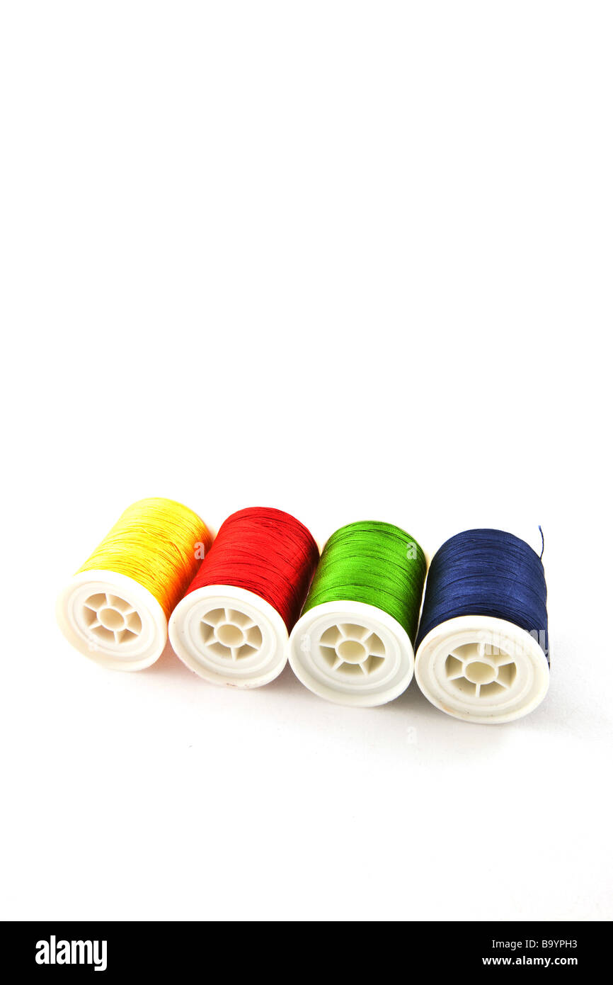 four multicolored spools on a white background Stock Photo - Alamy