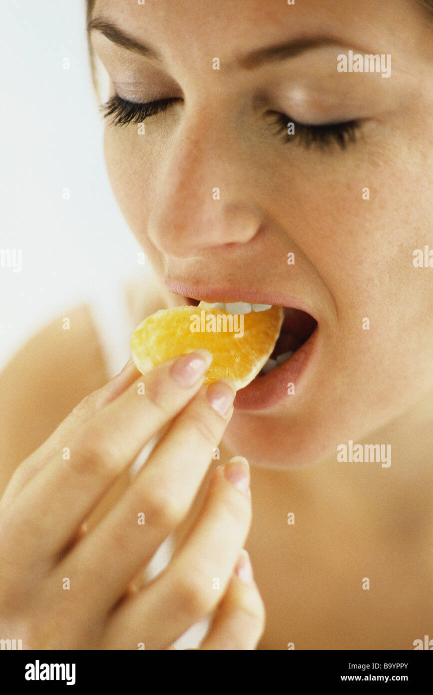 Woman biting into fruit Stock Photo - Alamy