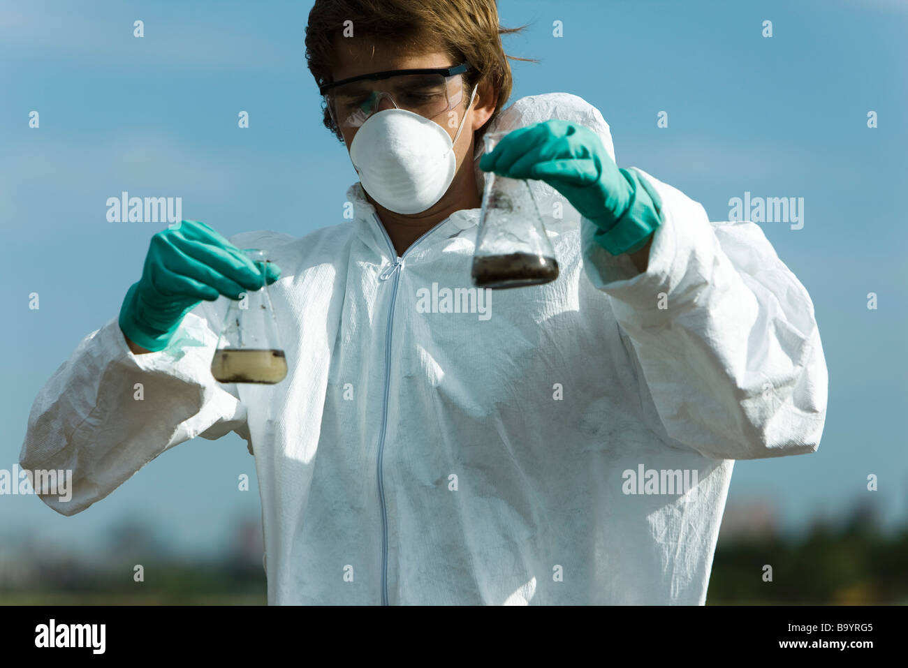 Person in protective suit holding flasks filled with polluted water ...