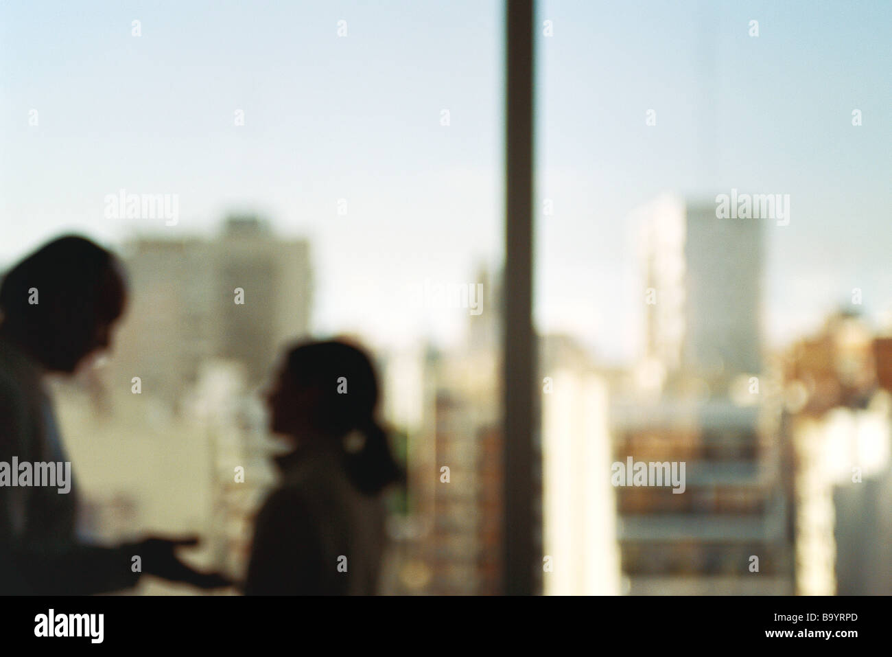 Man and woman face to face having conversation, window behind ...