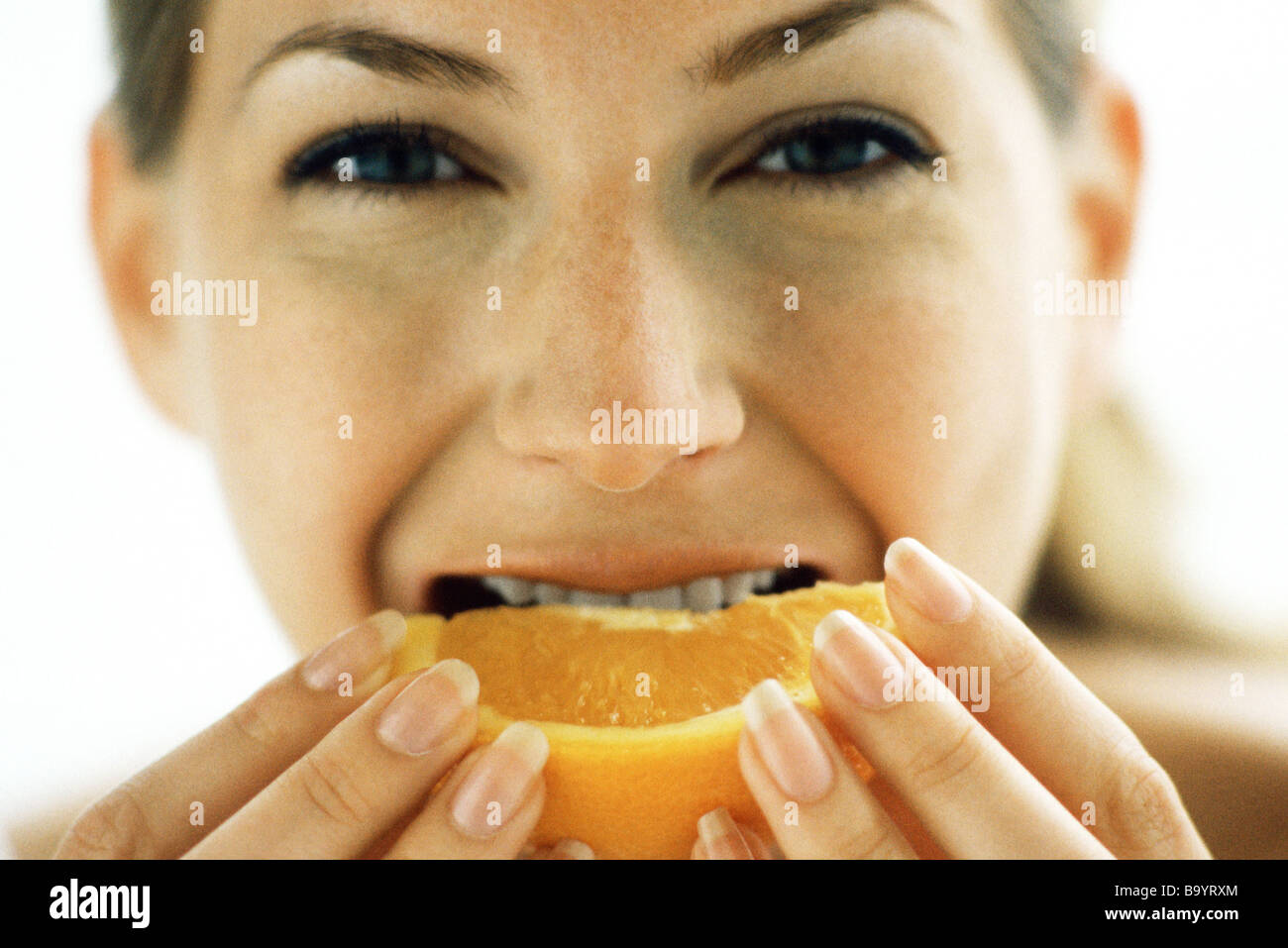 Woman biting into orange slice Stock Photo - Alamy