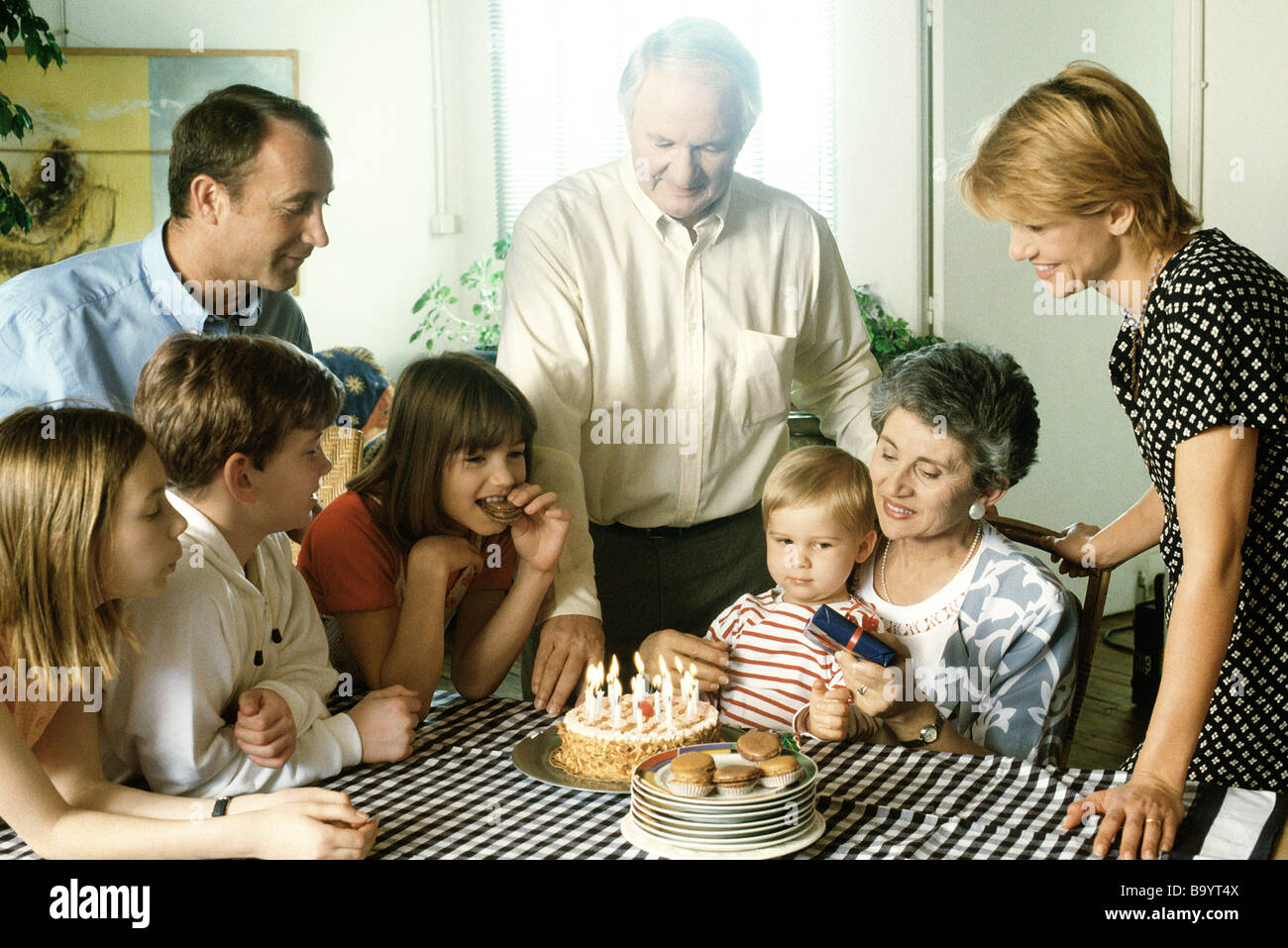 Family gathered around birthday cake Stock Photo - Alamy