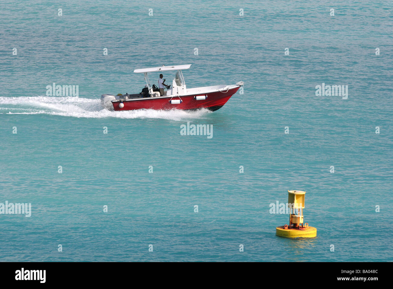 A red motor boat in blue water with a yellow buoy Stock Photo - Alamy