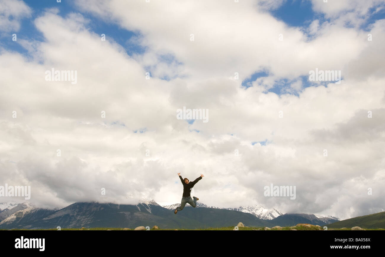 Person leaping on top of a mountain Stock Photo - Alamy