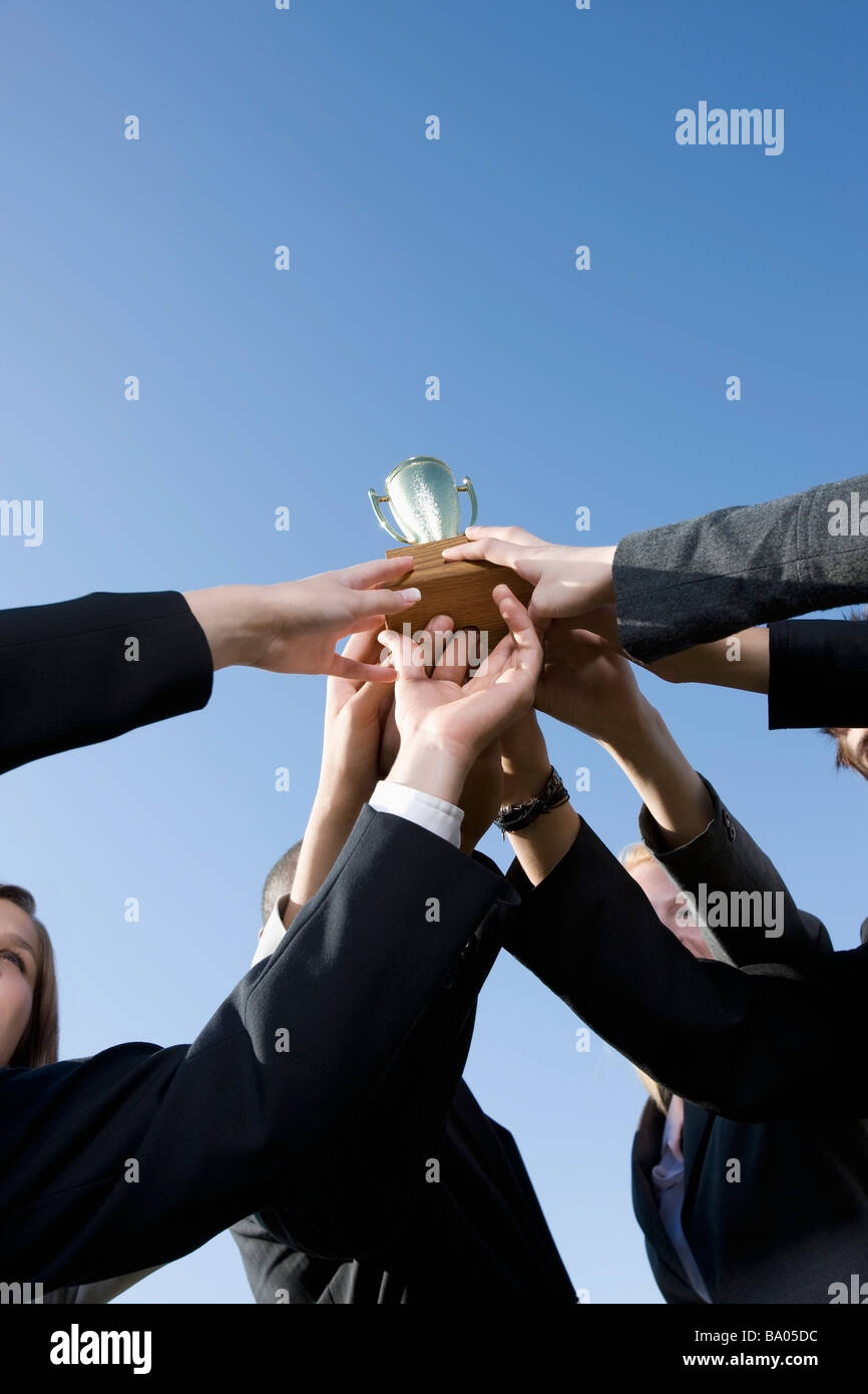 Group in business attire holding a trophy Stock Photo - Alamy