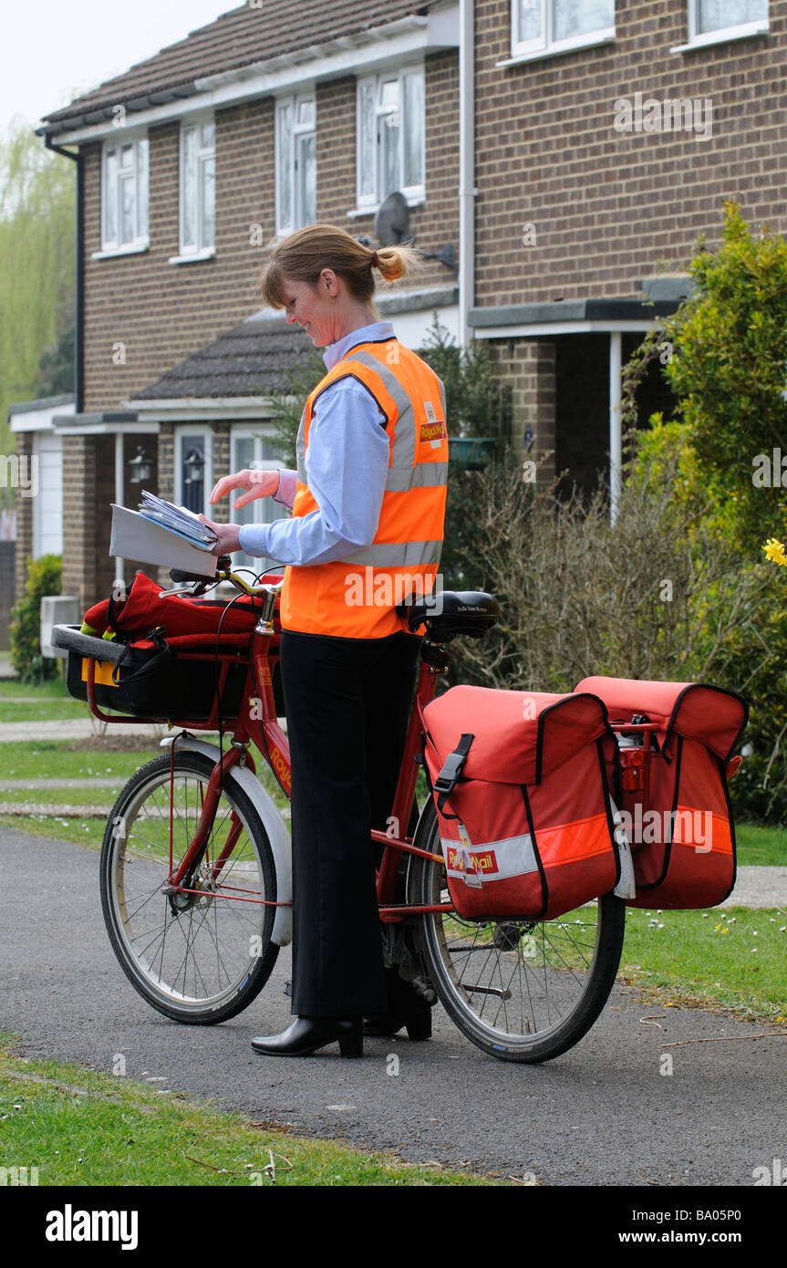 Royal Mail postwoman sorting letters on her round Stock Photo - Alamy