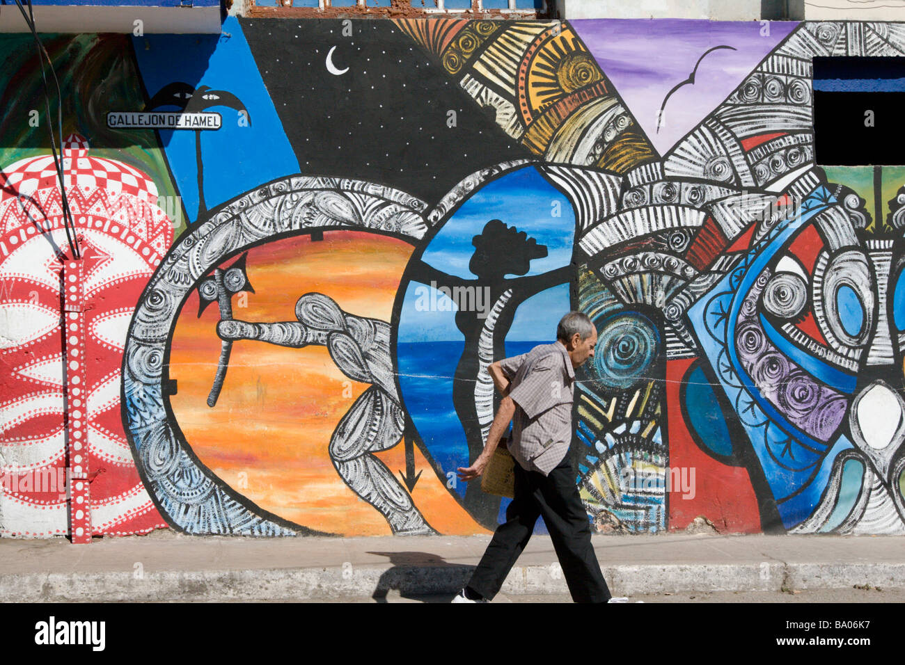 Old Cuban man walking past murals on Callejo de Hamel in Havana, Cuba ...