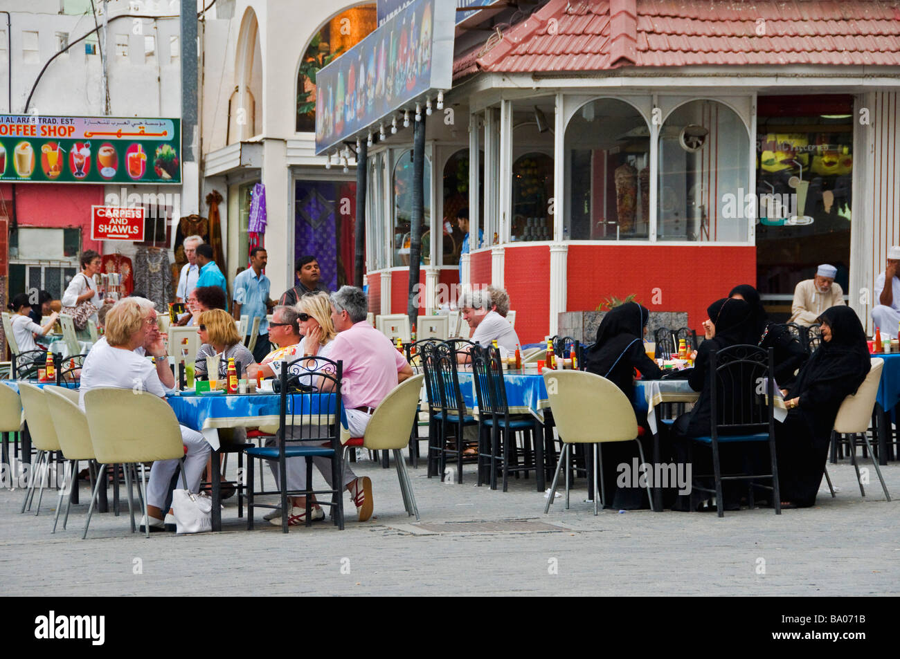 Local Omani women and foreigners on a terrace on the corniche Mutrah ...