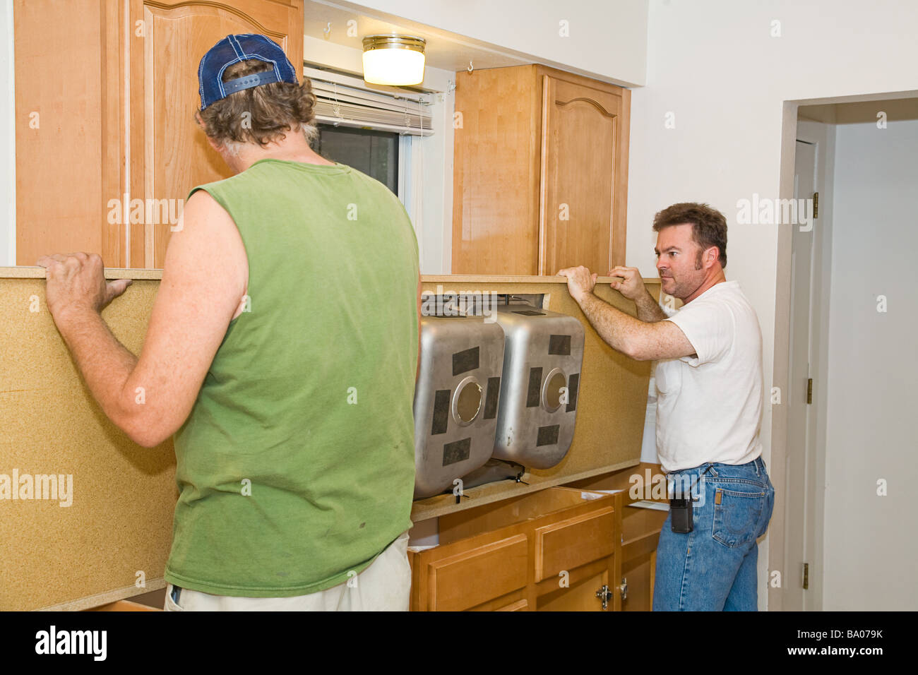 Carpenters installing a new laminate kitchen counter top and sink Focus ...