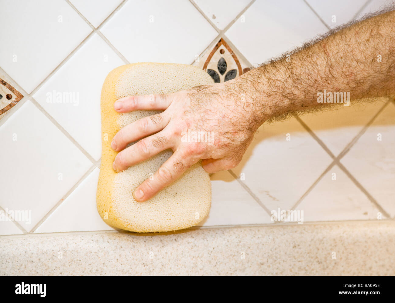 Worker s hand using a sponge to wipe fresh grout from ceramic tile ...