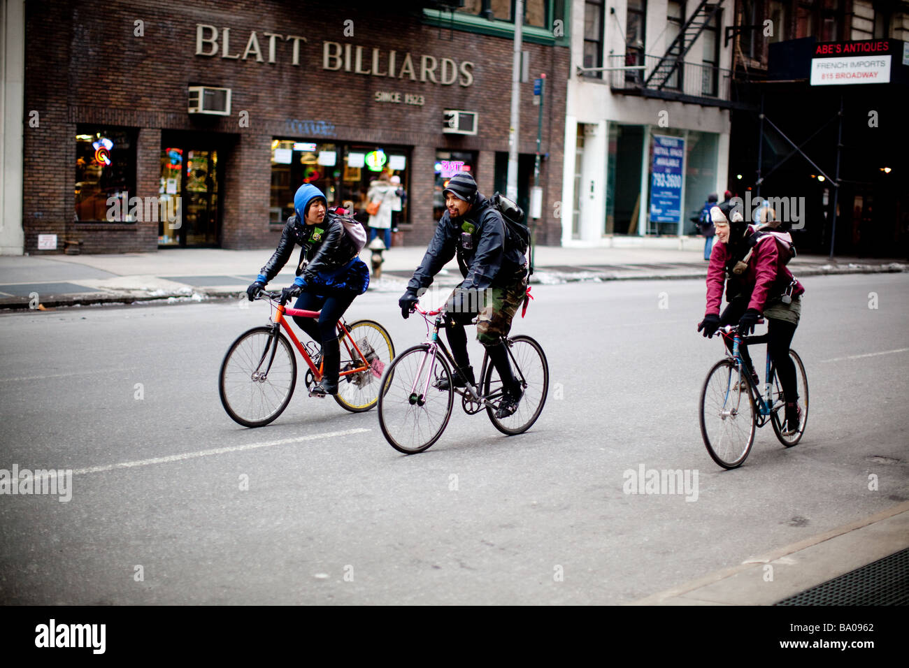 three people riding bicycles along a street in New York near Union ...