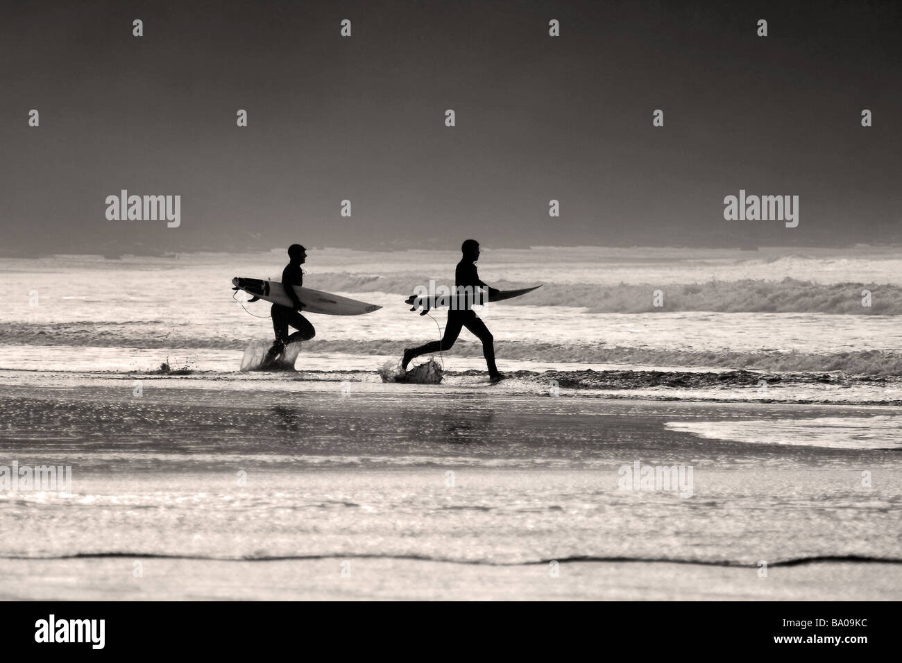 Two surfers run into the waves at Chesterman's Beach near Tofino, on ...
