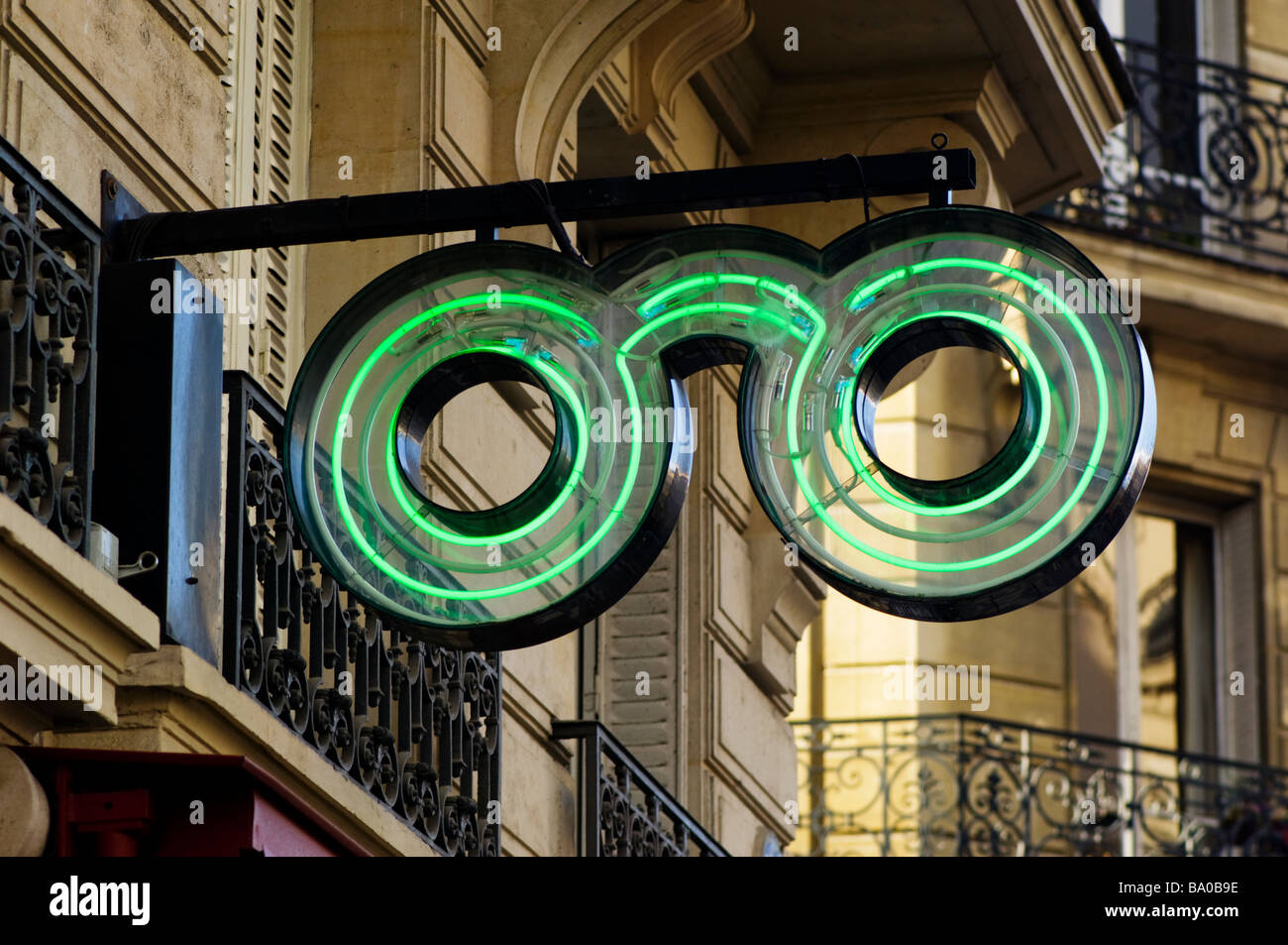 Optometrist neon sign with large glasses hung from a building in Paris ...
