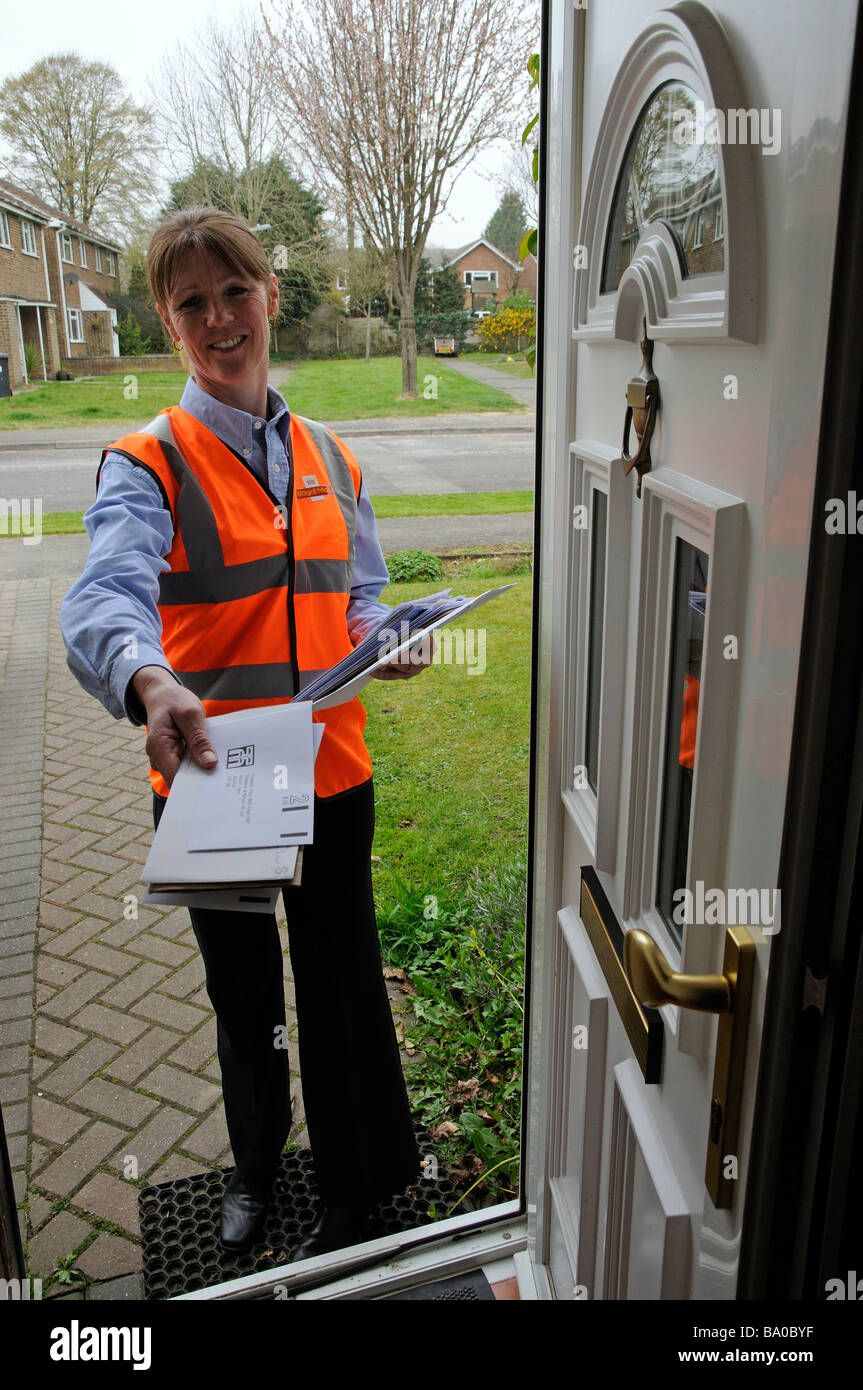 royal mail postwoman at the front door of a house delivering mail to a ...