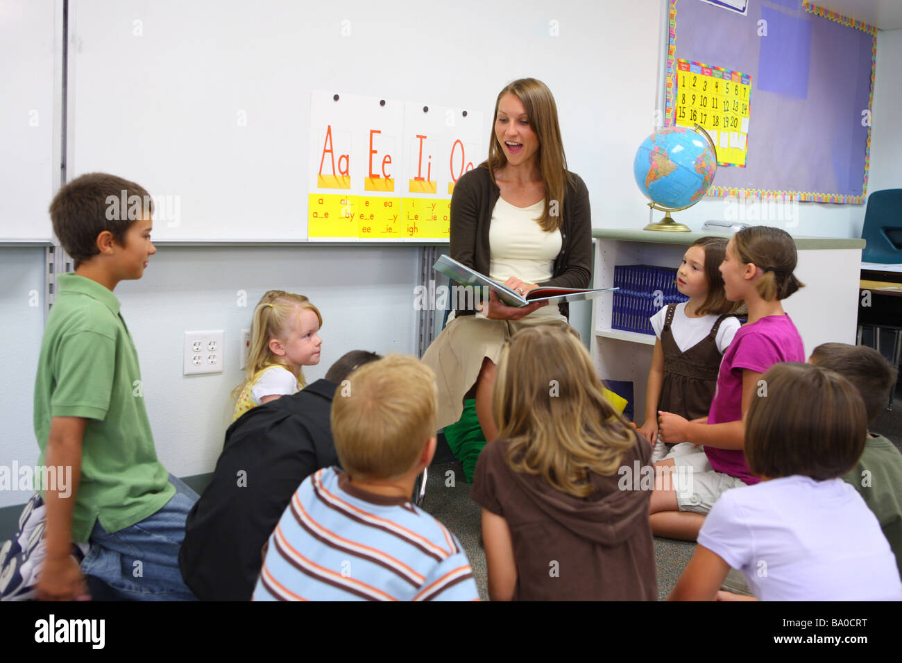 School teacher reading to group of students Stock Photo - Alamy