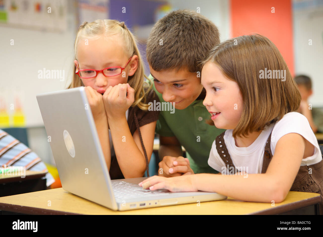 Three school children looking at laptop computer Stock Photo - Alamy