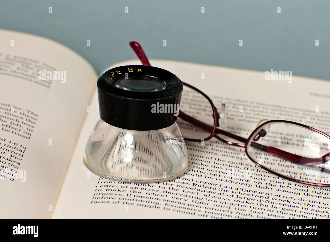 Open book with reading glasses and a magnifying lupe Stock Photo - Alamy